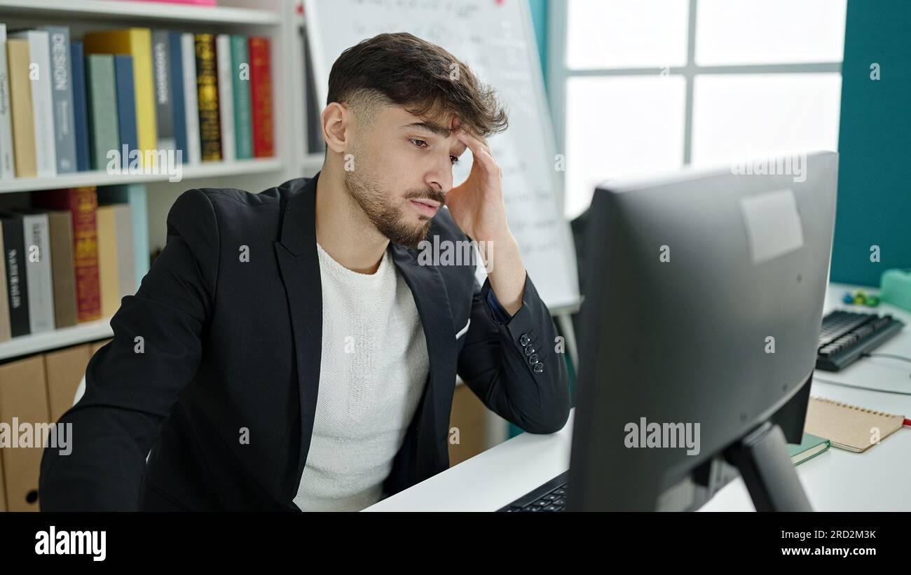 Young arab man student using computer studying at university classroom ...