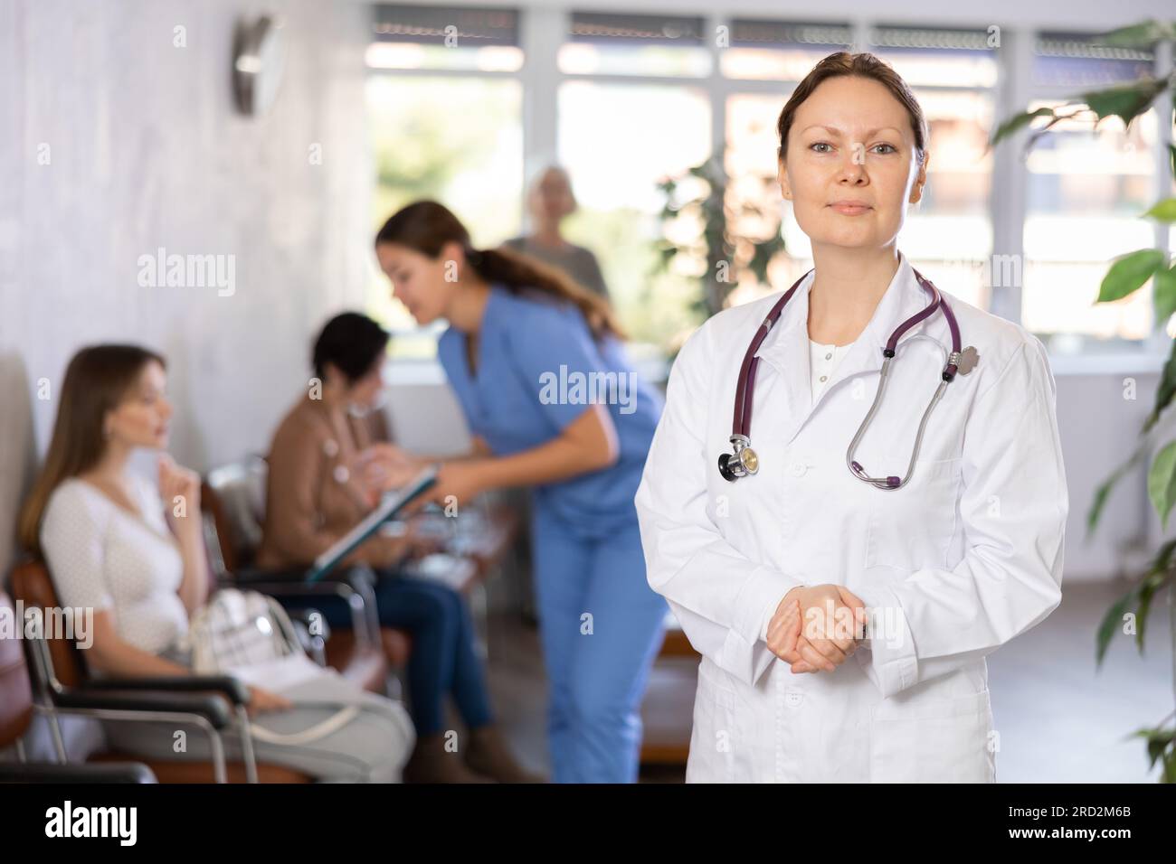 Smiling polite female doctor standing in busy clinic lobby Stock Photo ...