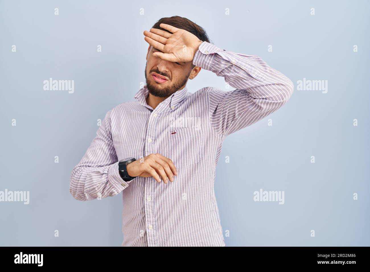 Arab man with beard standing over blue background touching forehead for ...
