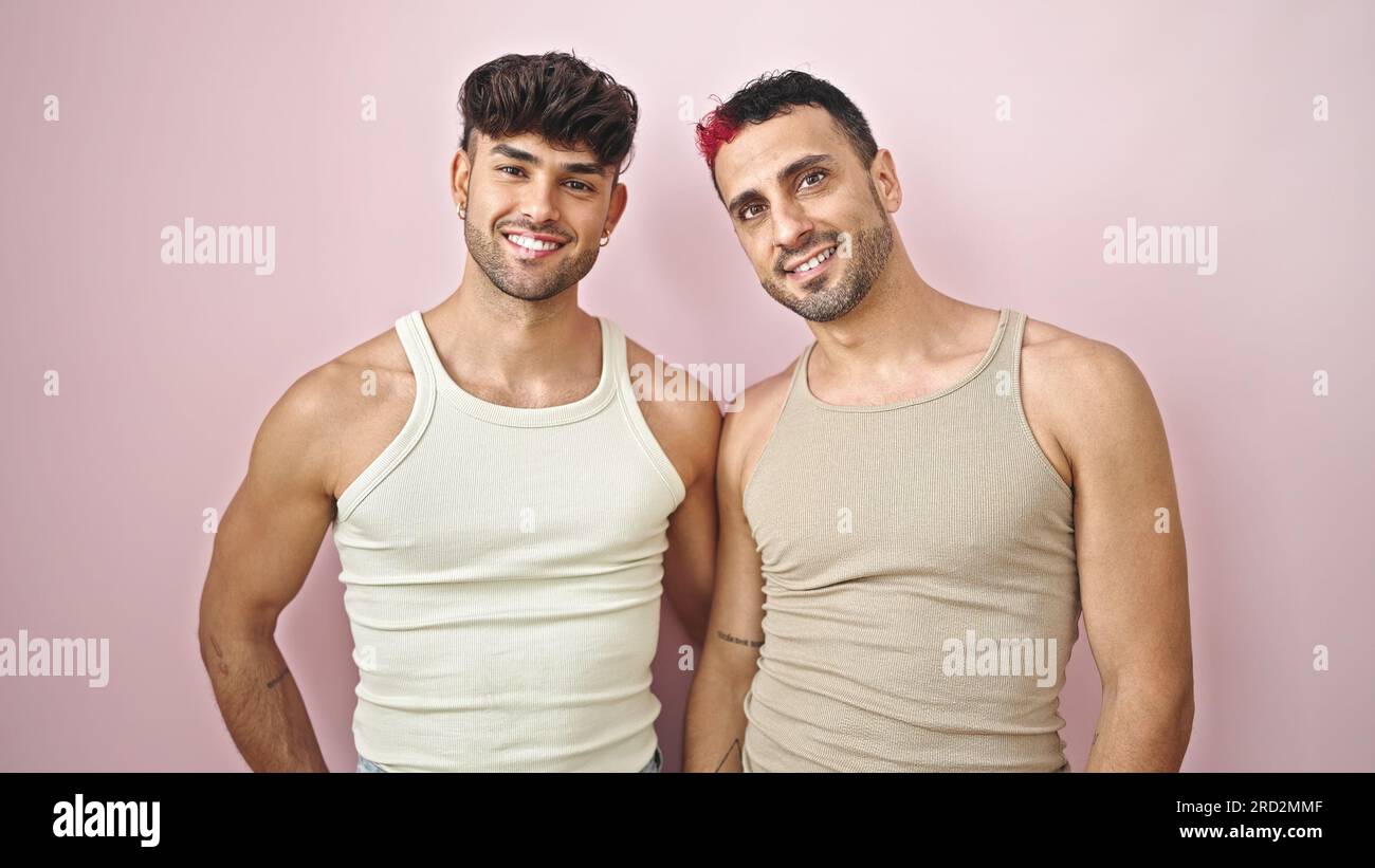 Two men couple smiling confident standing together over isolated pink ...