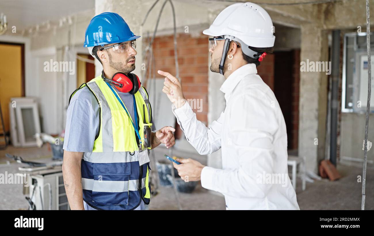 Two men builder and architect standing together speaking at ...