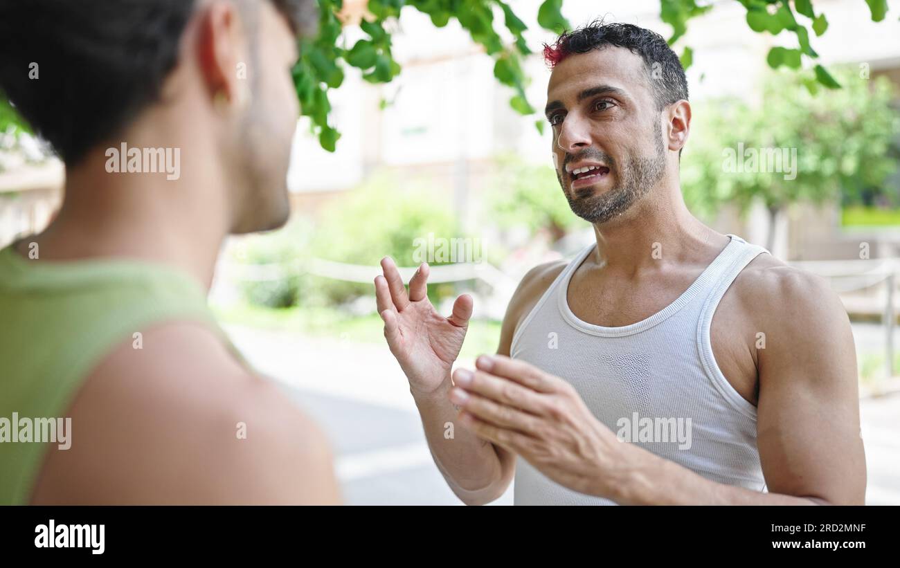 Two men couple smiling confident speaking at park Stock Photo - Alamy