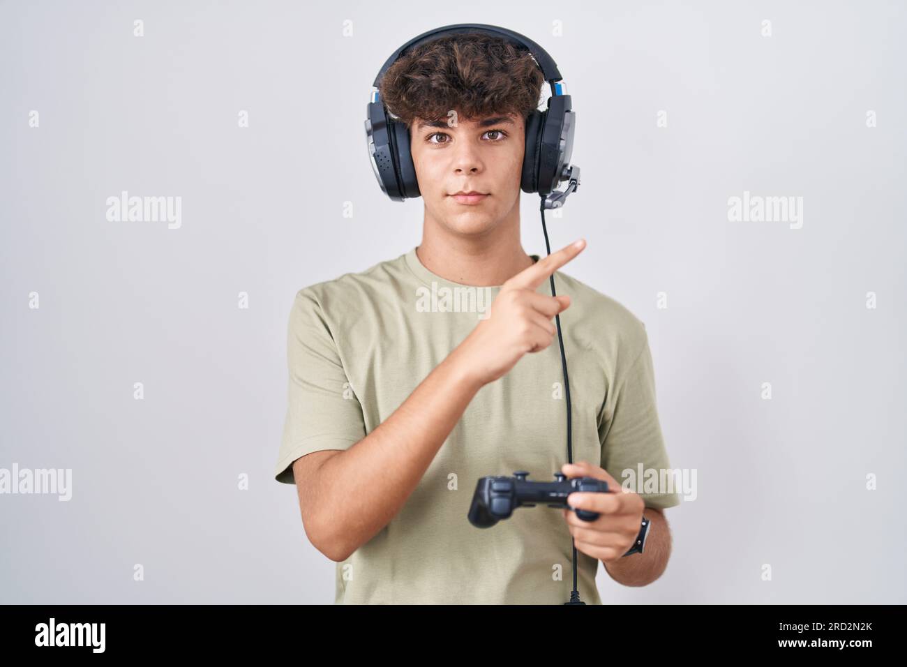 Hispanic teenager playing video game holding controller pointing with ...