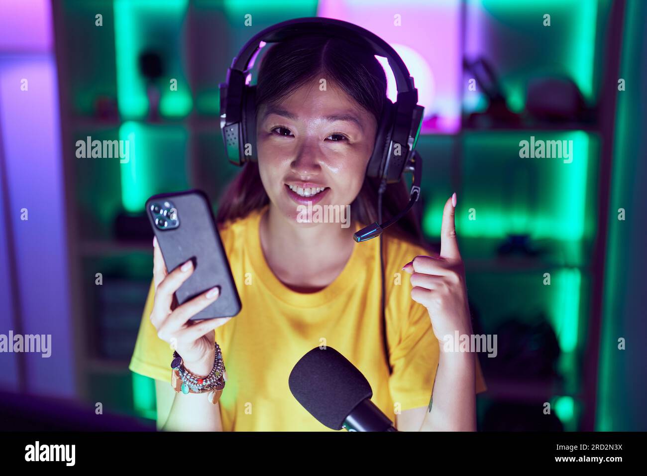 Chinese young woman playing video games with smartphone smiling with an ...