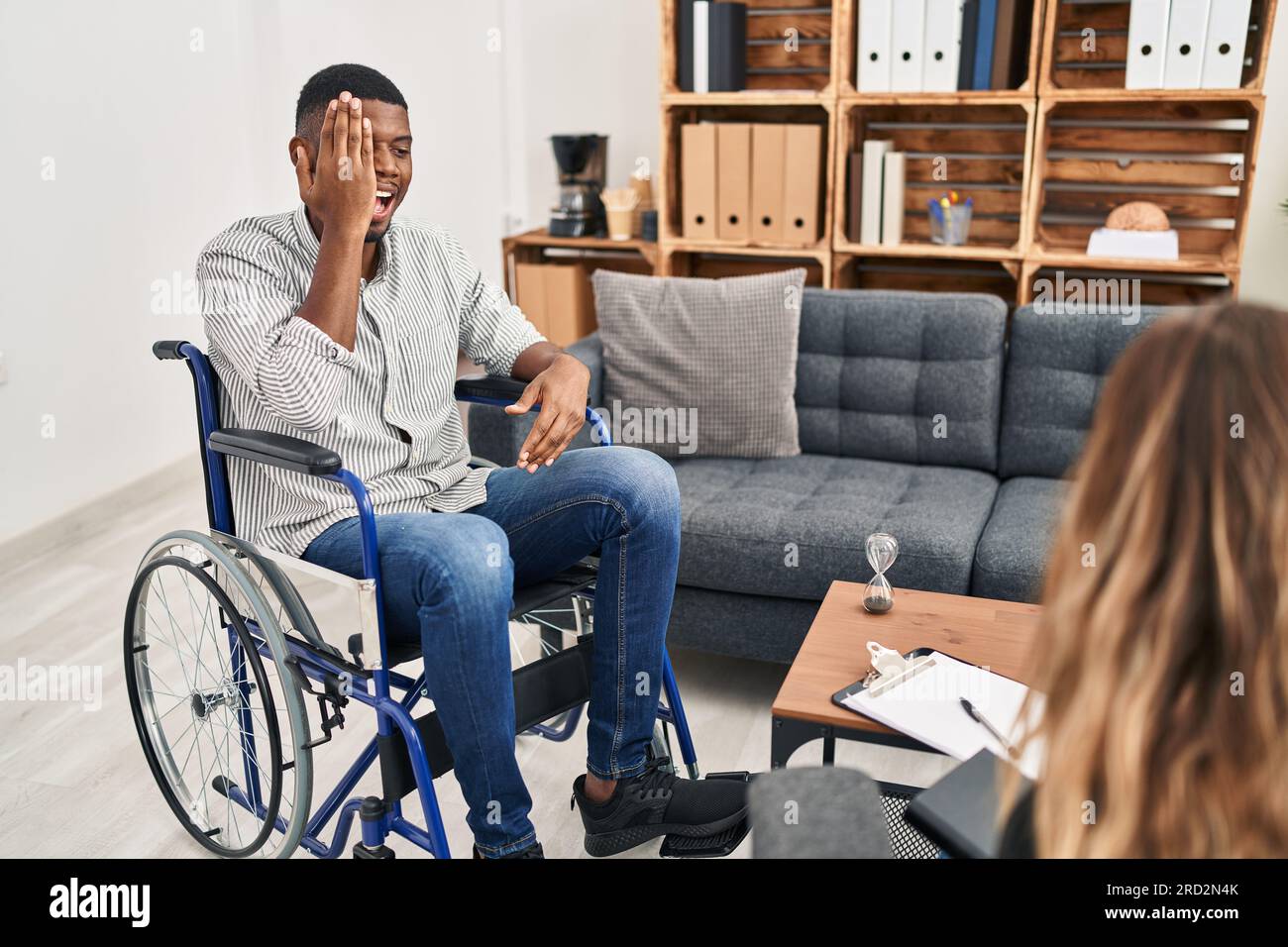 African american man doing therapy sitting on wheelchair covering one ...