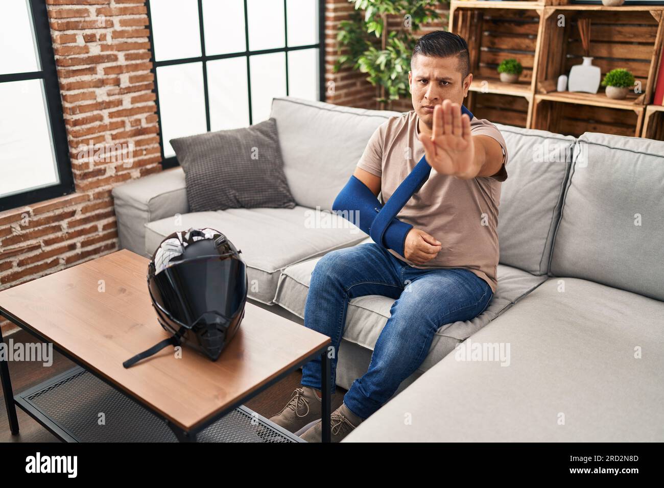 Hispanic young man wearing arm on sling for motorbike accident with ...