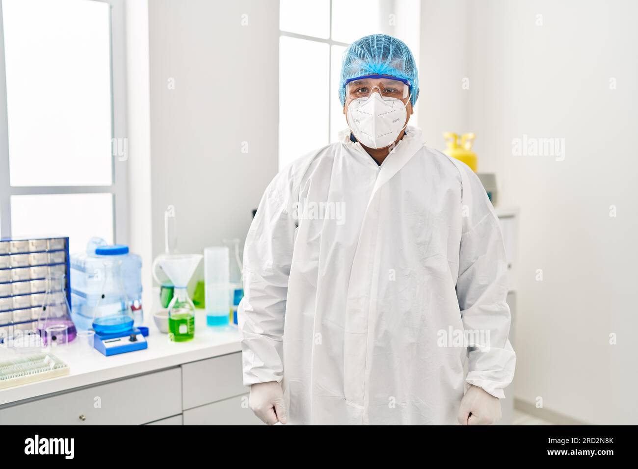 Young latin man scientist wearing covid protection uniform standing at ...