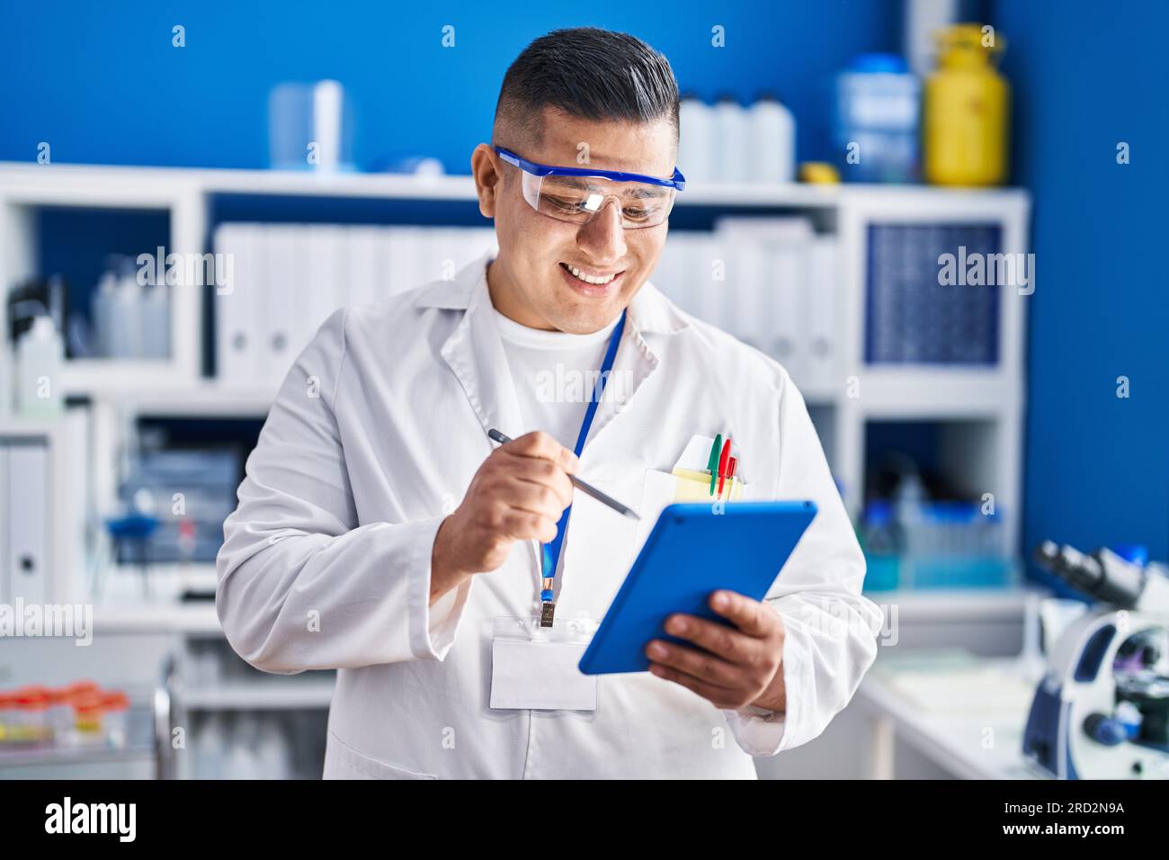 Young latin man scientist smiling confident using touchpad at laboratory Stock Photo - Alamy