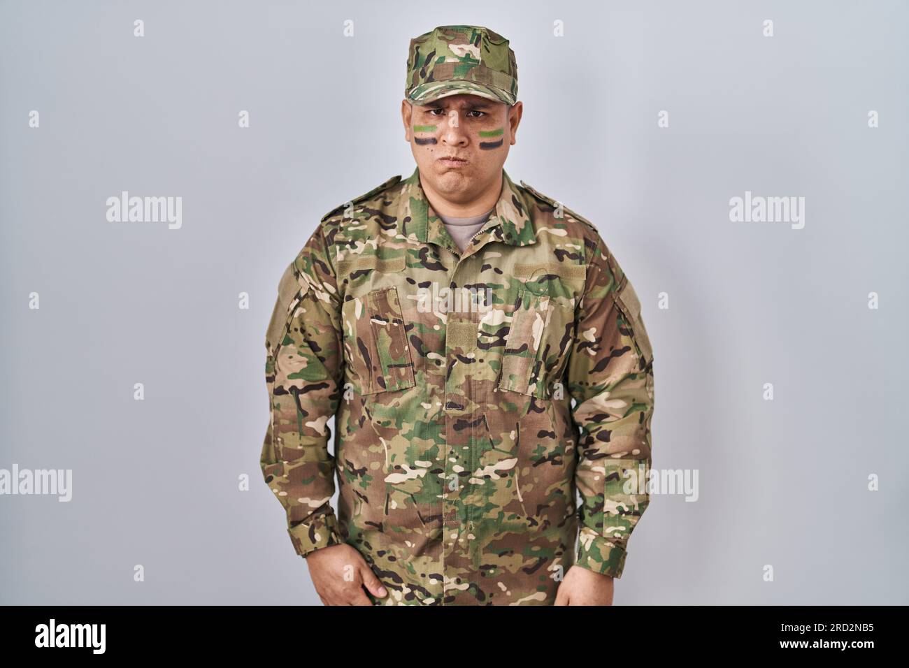Hispanic young man wearing camouflage army uniform skeptic and nervous ...