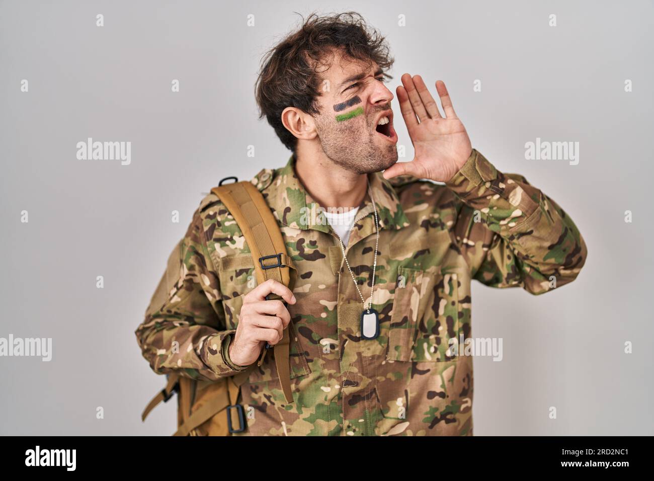 Hispanic young man wearing camouflage army uniform shouting and ...