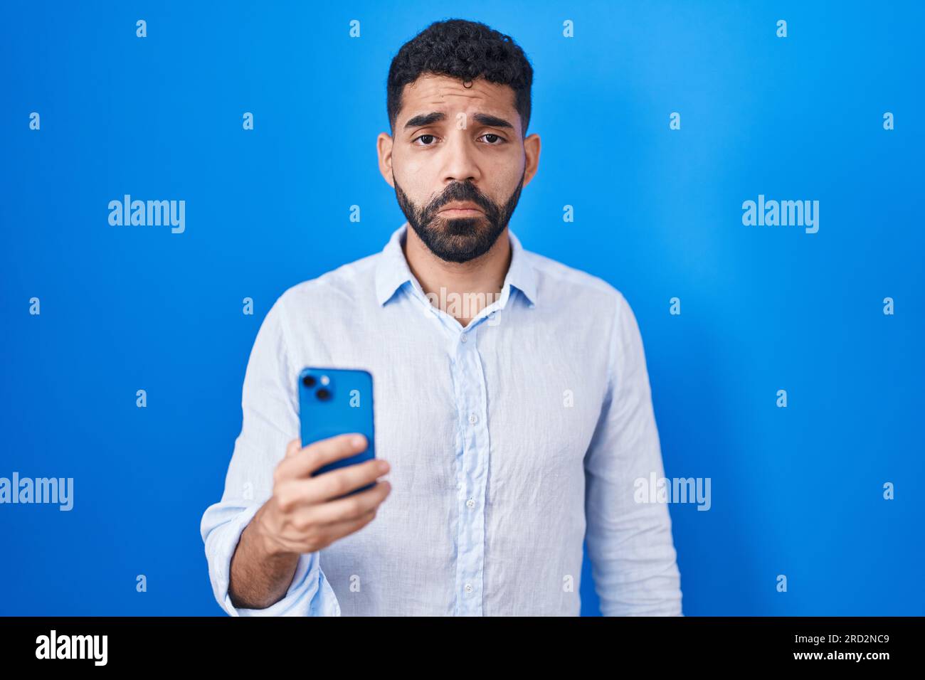 Hispanic man with beard using smartphone typing message depressed and ...