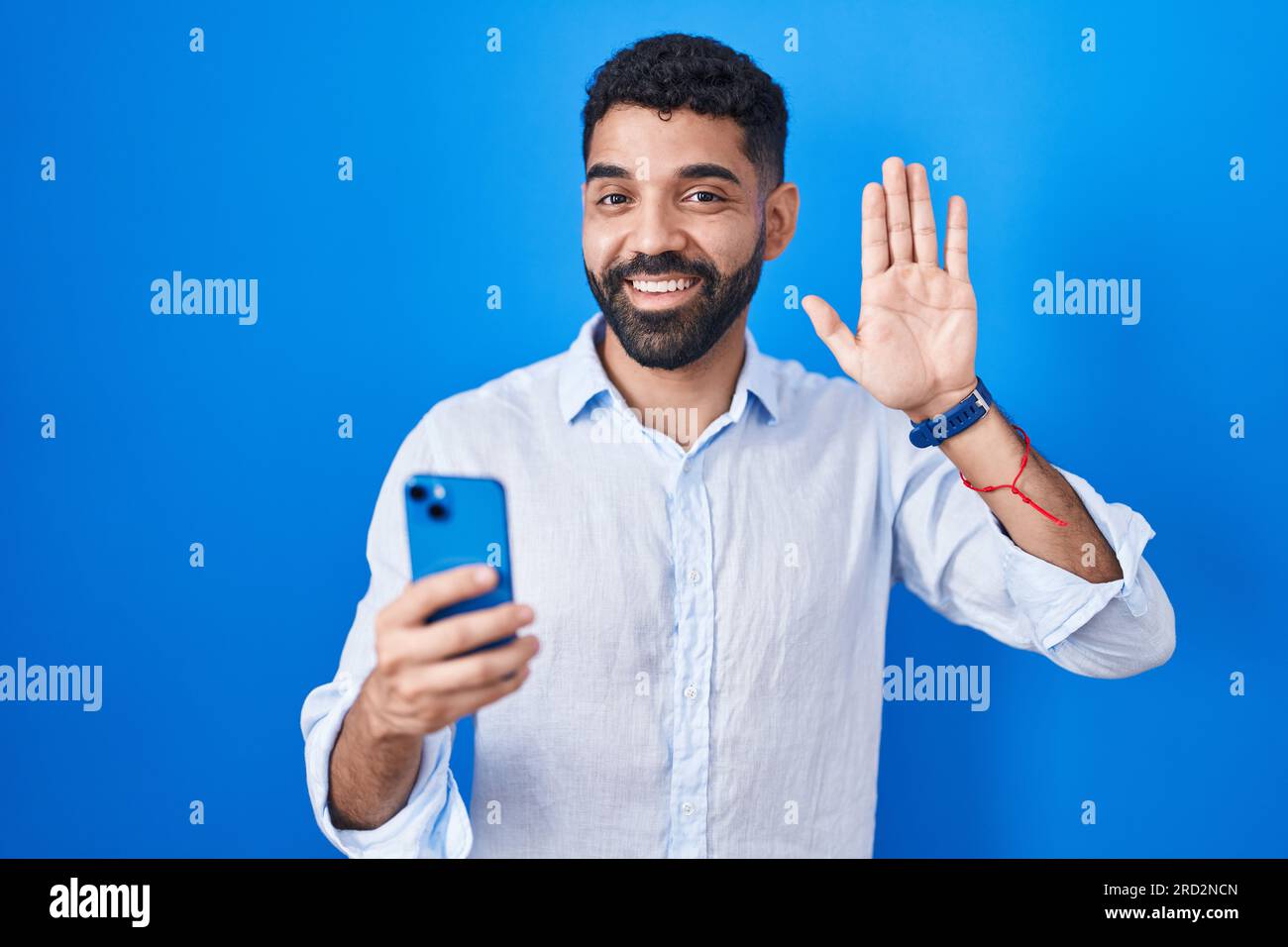 Hispanic Man With Beard Using Smartphone Typing Message Waiving Saying