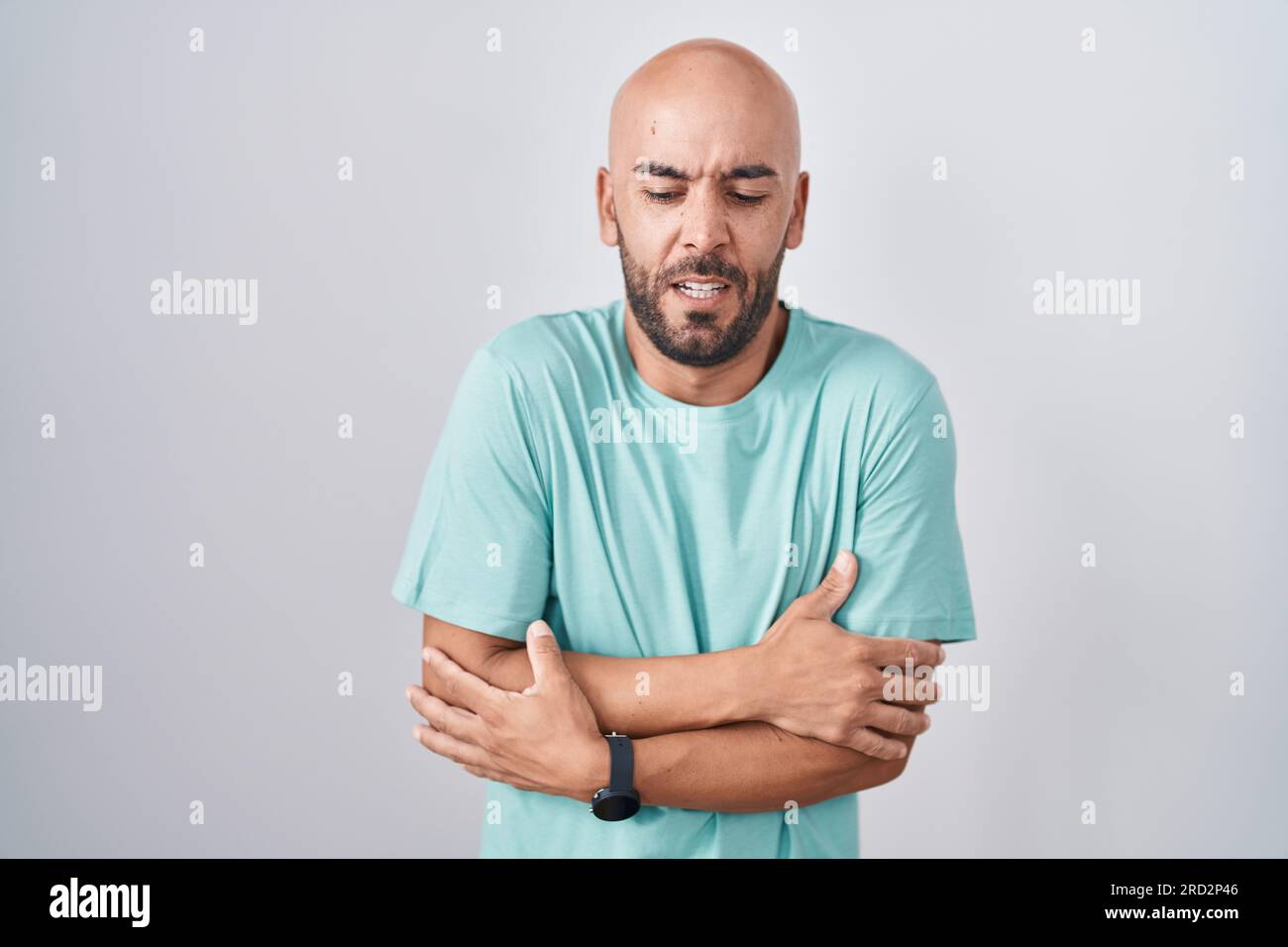 Middle age bald man standing over white background shaking and freezing ...