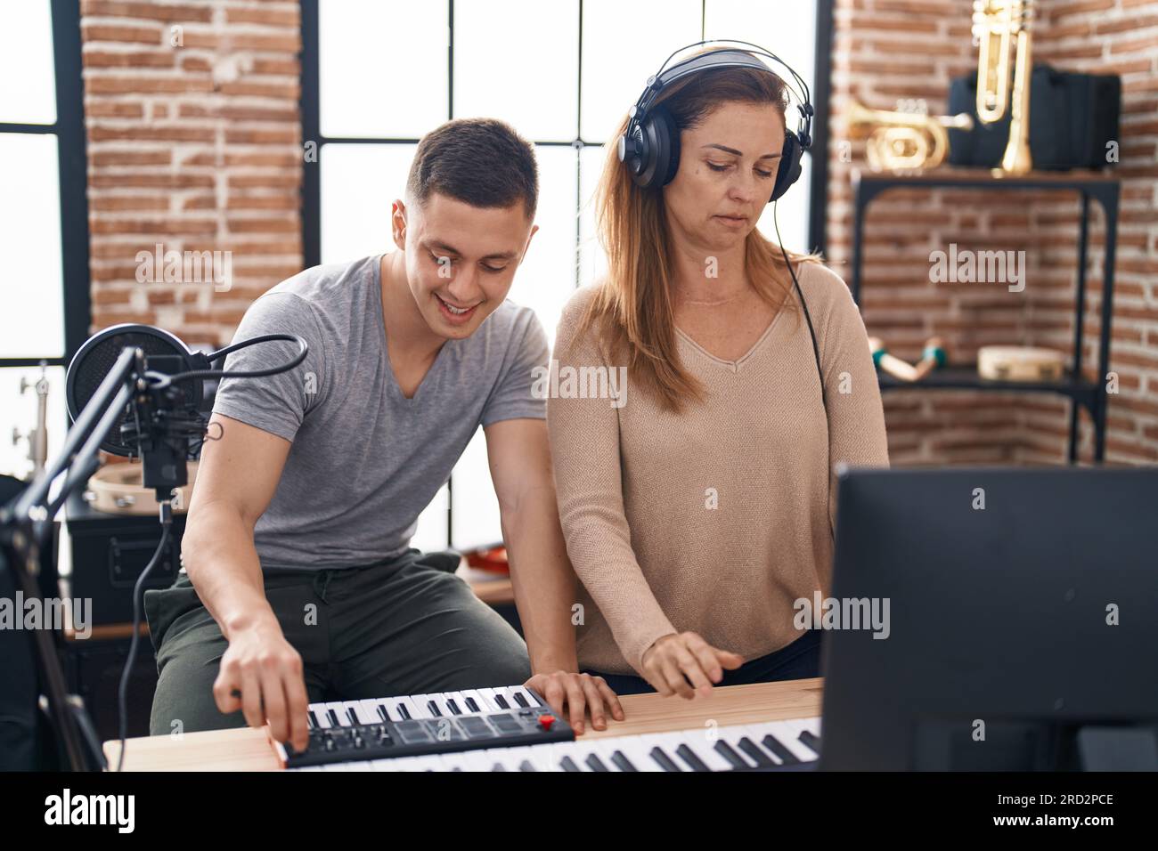 Man and woman musicians playing piano keyboard at music studio Stock ...