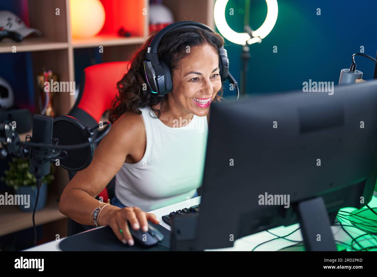 Middle age woman streamer playing video game using computer at gaming ...