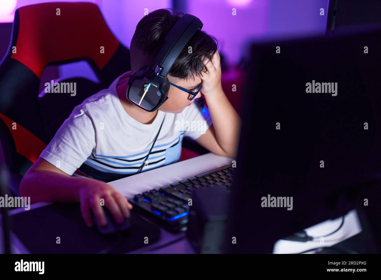 Adorable hispanic boy streamer stressed using computer at gaming room ...