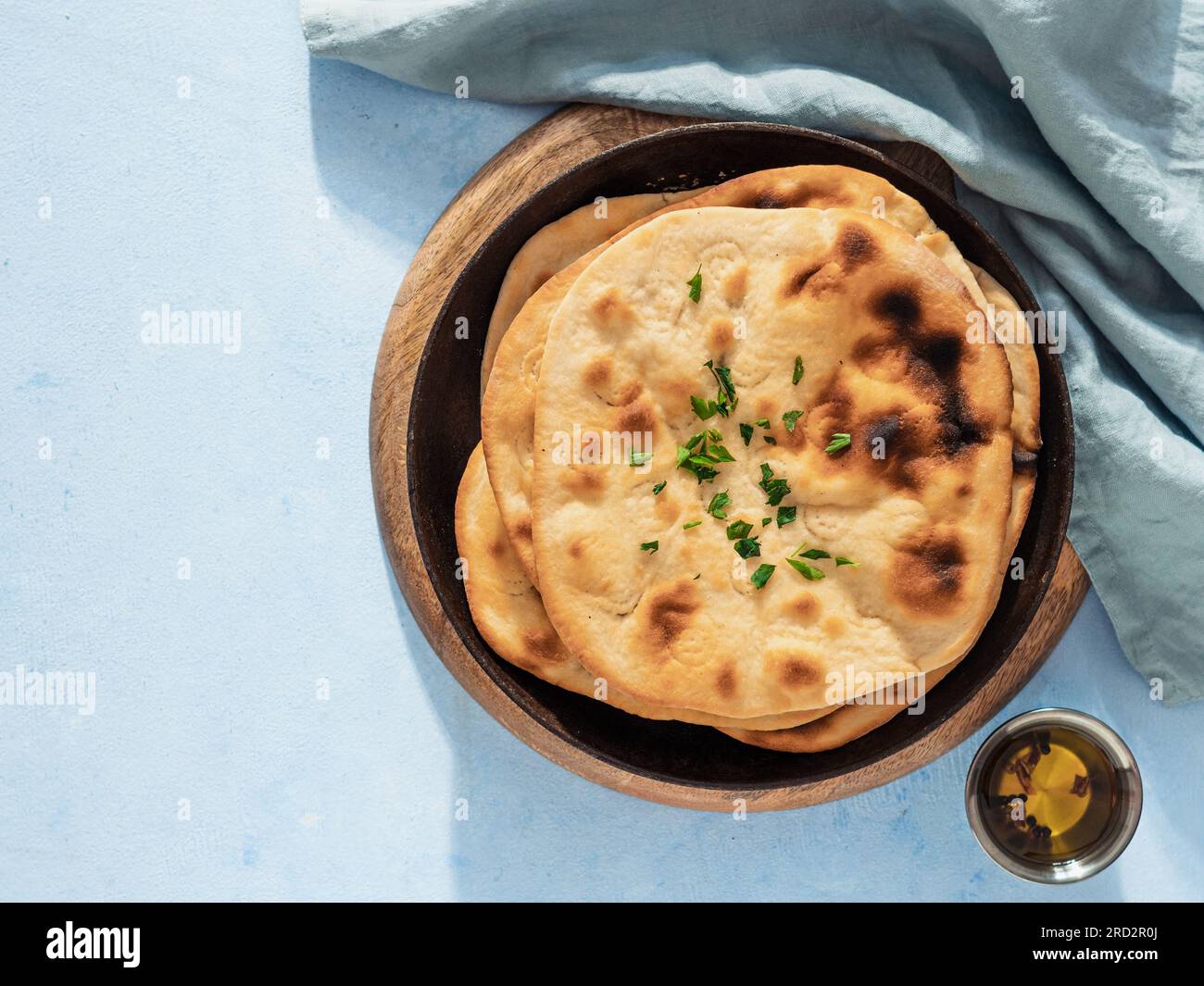 Stack of fesh naan breads in cast-iron pan on blue background with copy ...