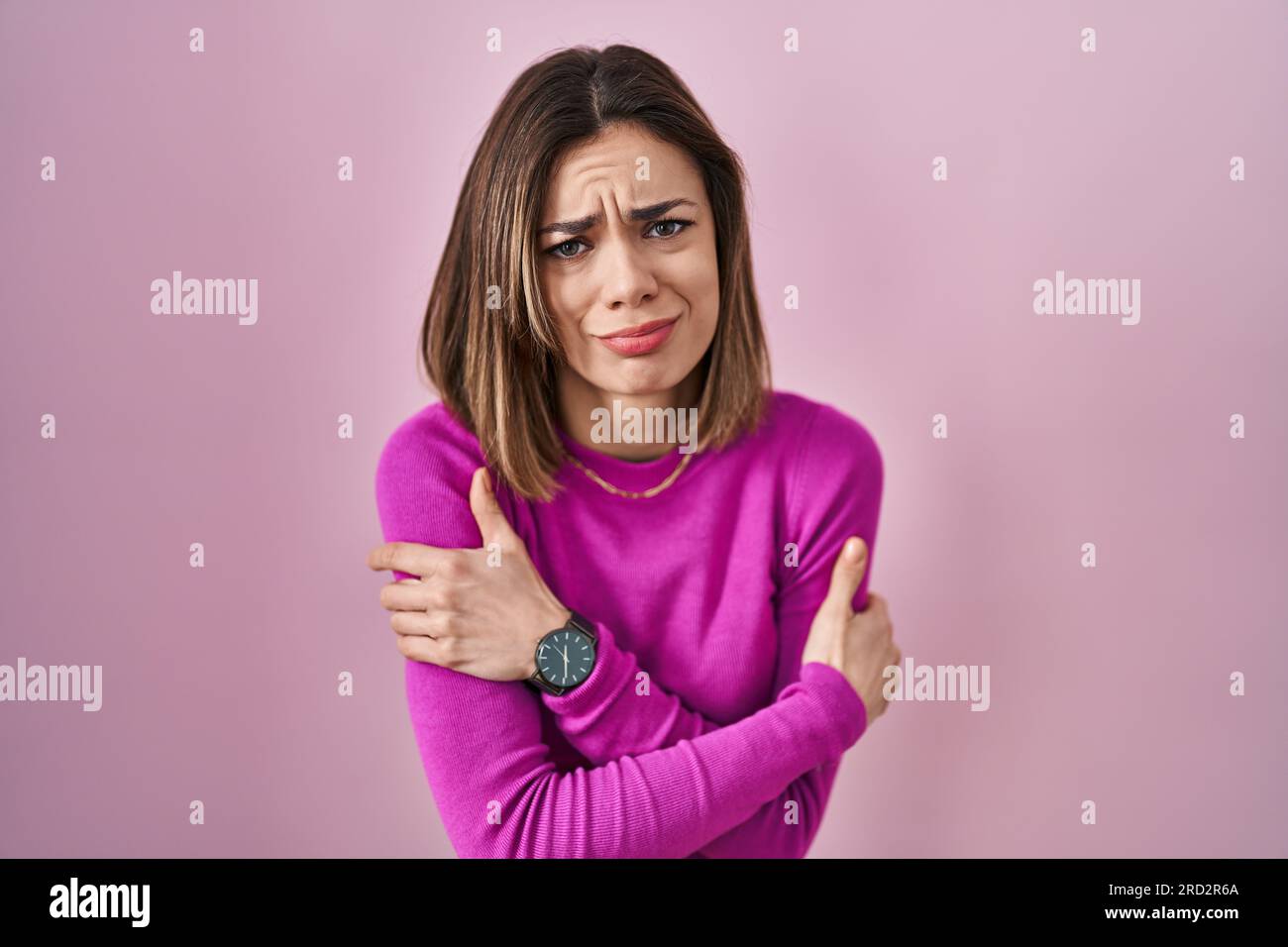 Hispanic woman standing over pink background shaking and freezing for ...