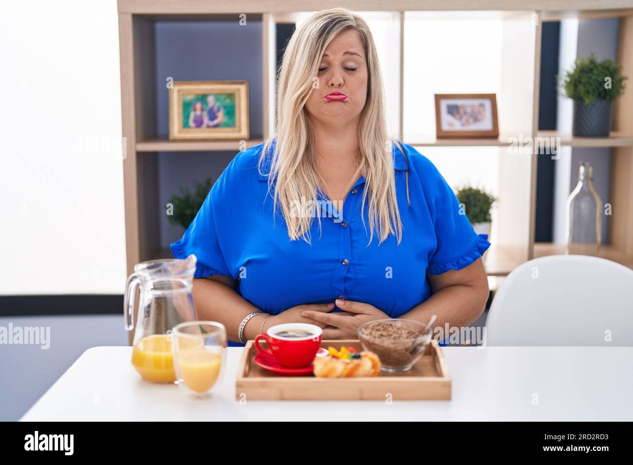 Caucasian plus size woman eating breakfast at home depressed and worry ...