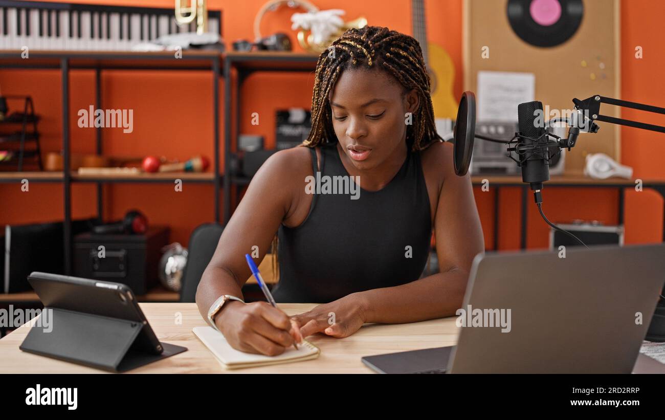 African american woman musician writing on paperwork composing song at ...