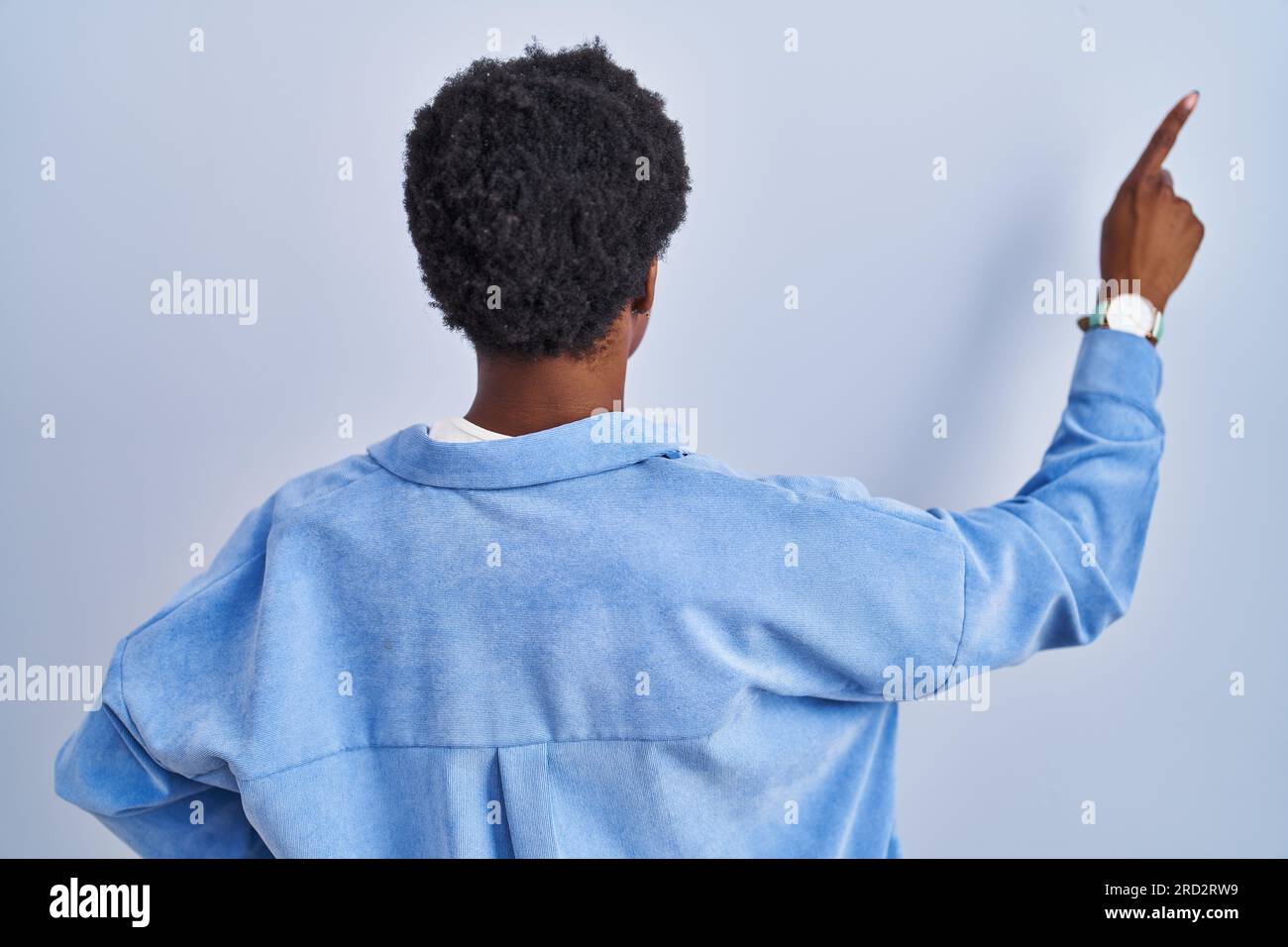 African american woman standing over blue background posing backwards ...