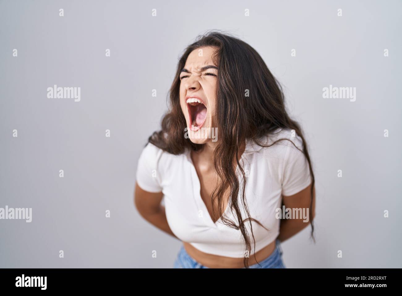 Young teenager girl standing over white background angry and mad ...