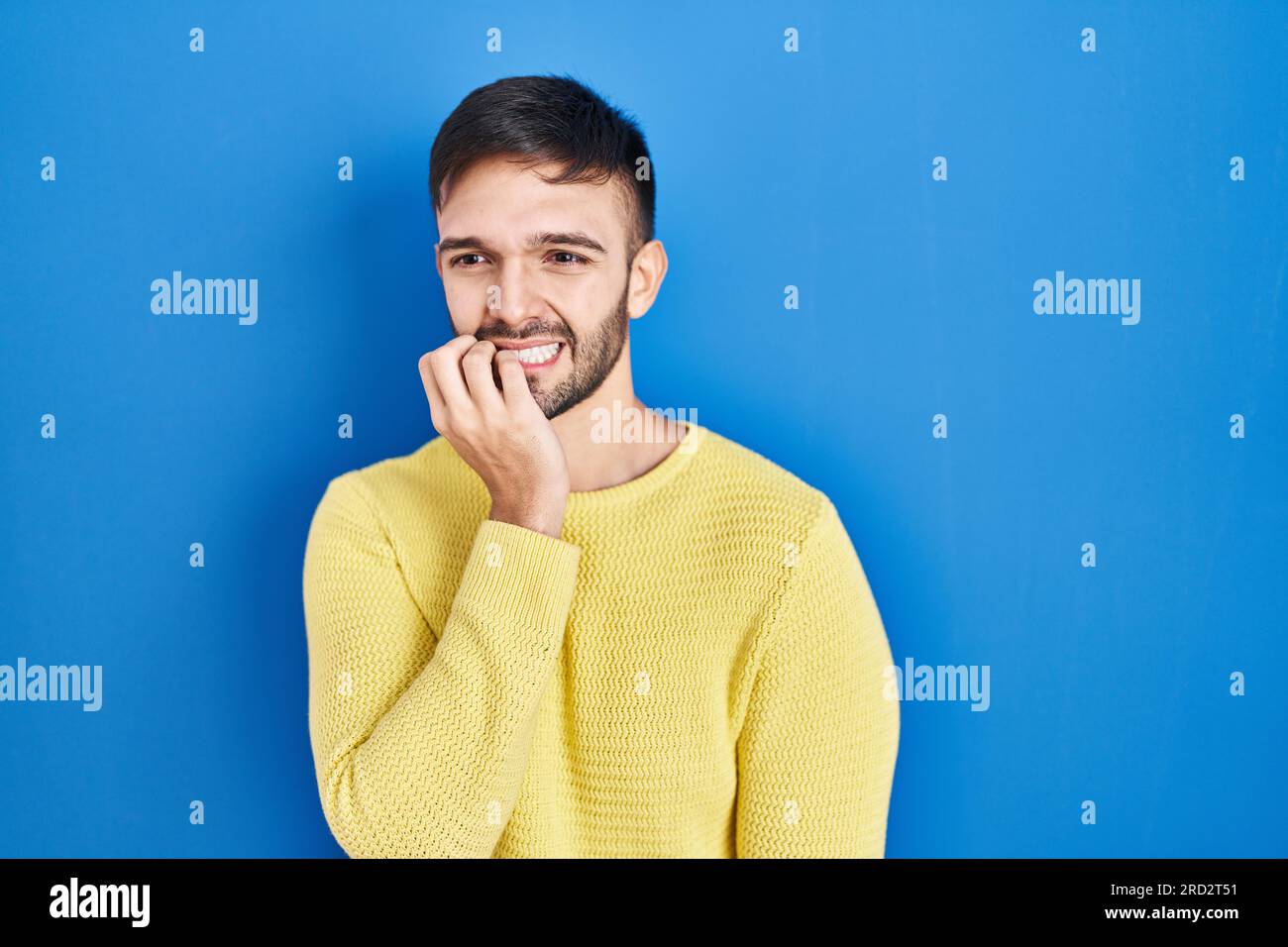 Hispanic man standing over blue background looking stressed and nervous ...