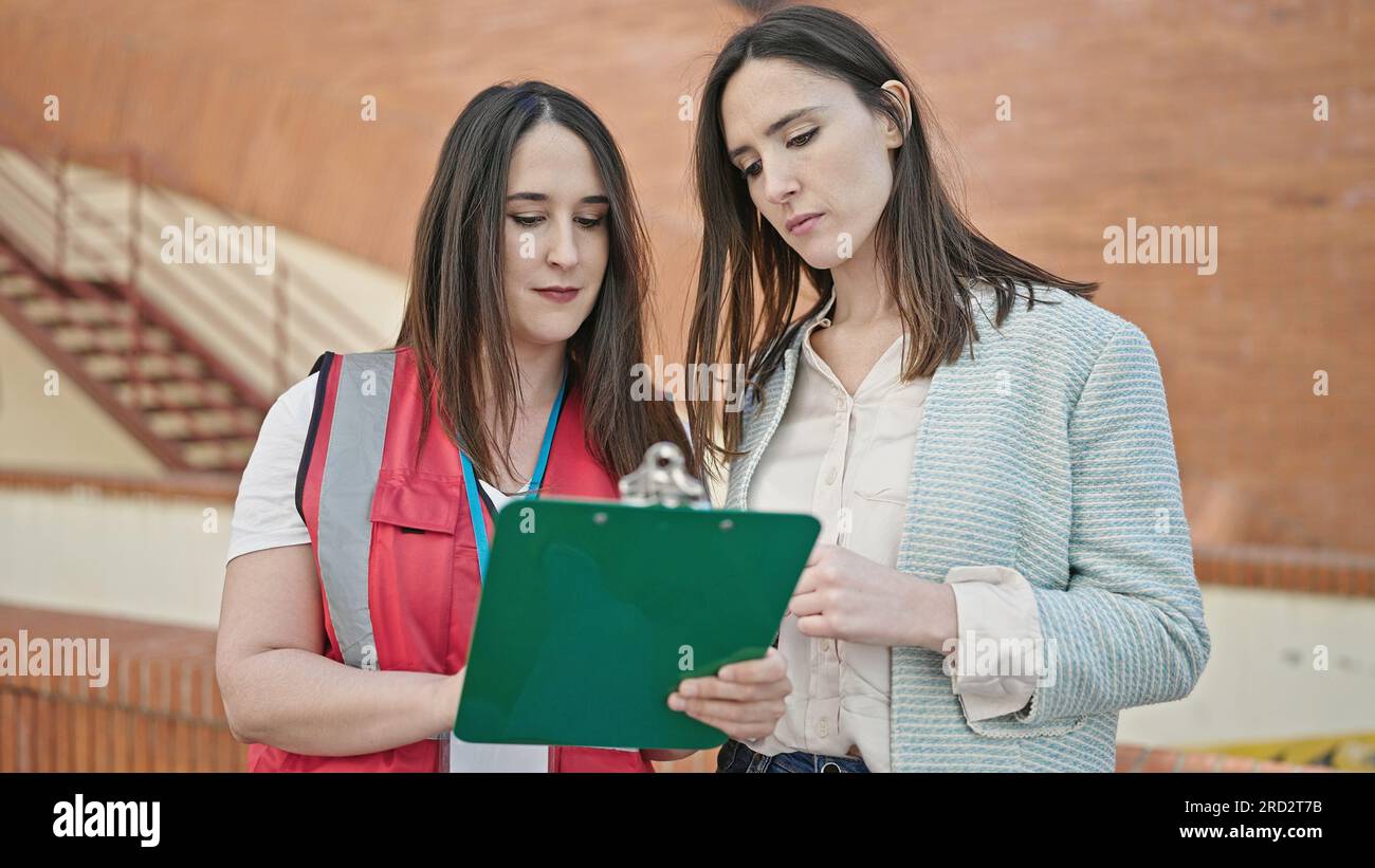 Two women having survey interview writing on clipboard at street Stock ...