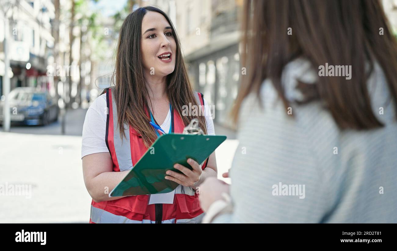 Two women having survey interview writing on clipboard at street Stock ...