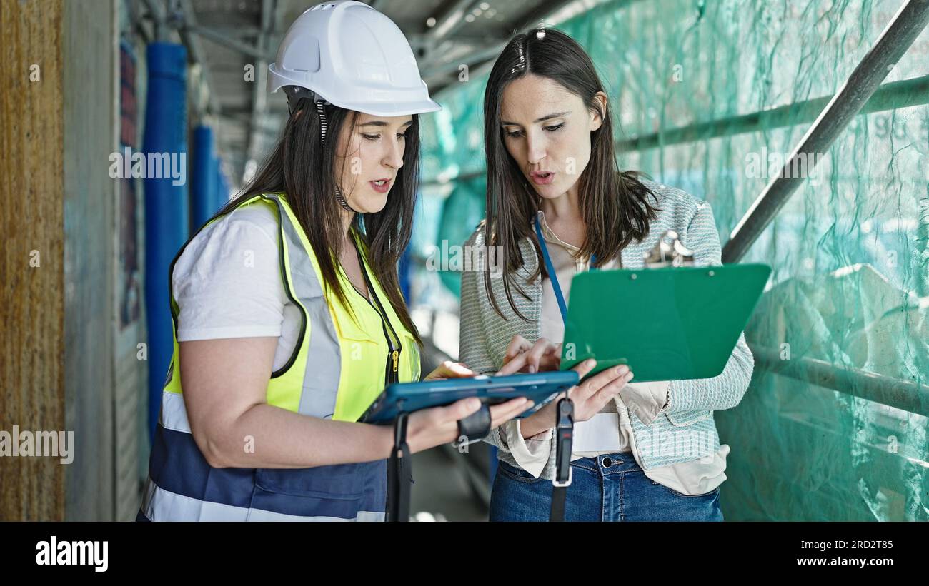 Two women architect and worker using touchpad and clipboard working at ...