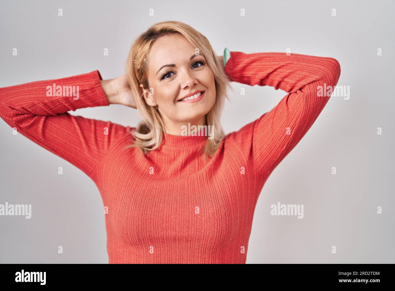 Blonde woman standing over isolated background relaxing and stretching ...