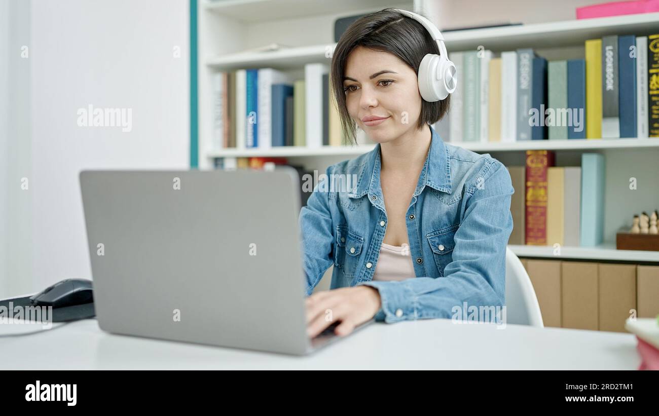 Young caucasian woman student using computer wearing headphones at ...