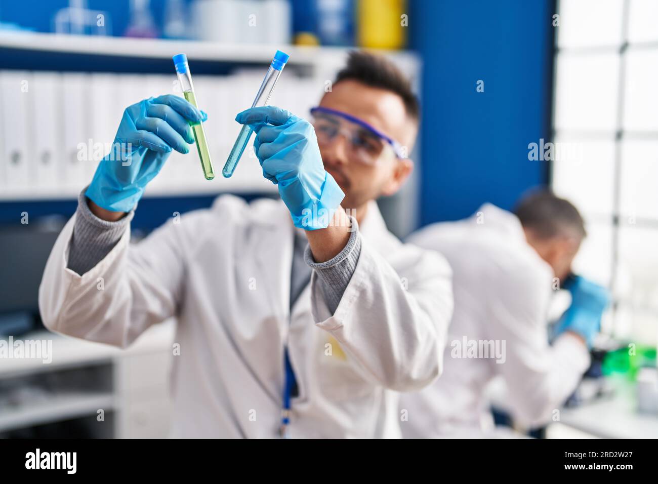 Two men scientists holding test tubes using microscope at laboratory ...