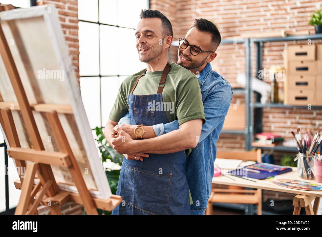 Two men artists hugging each other looking draw at art studio Stock ...