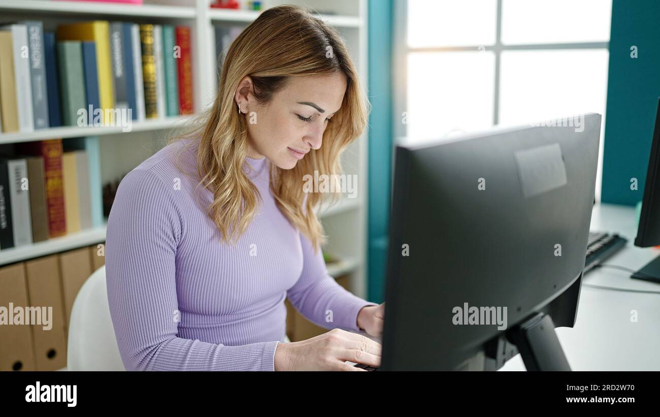 Young beautiful hispanic woman student using computer at library ...