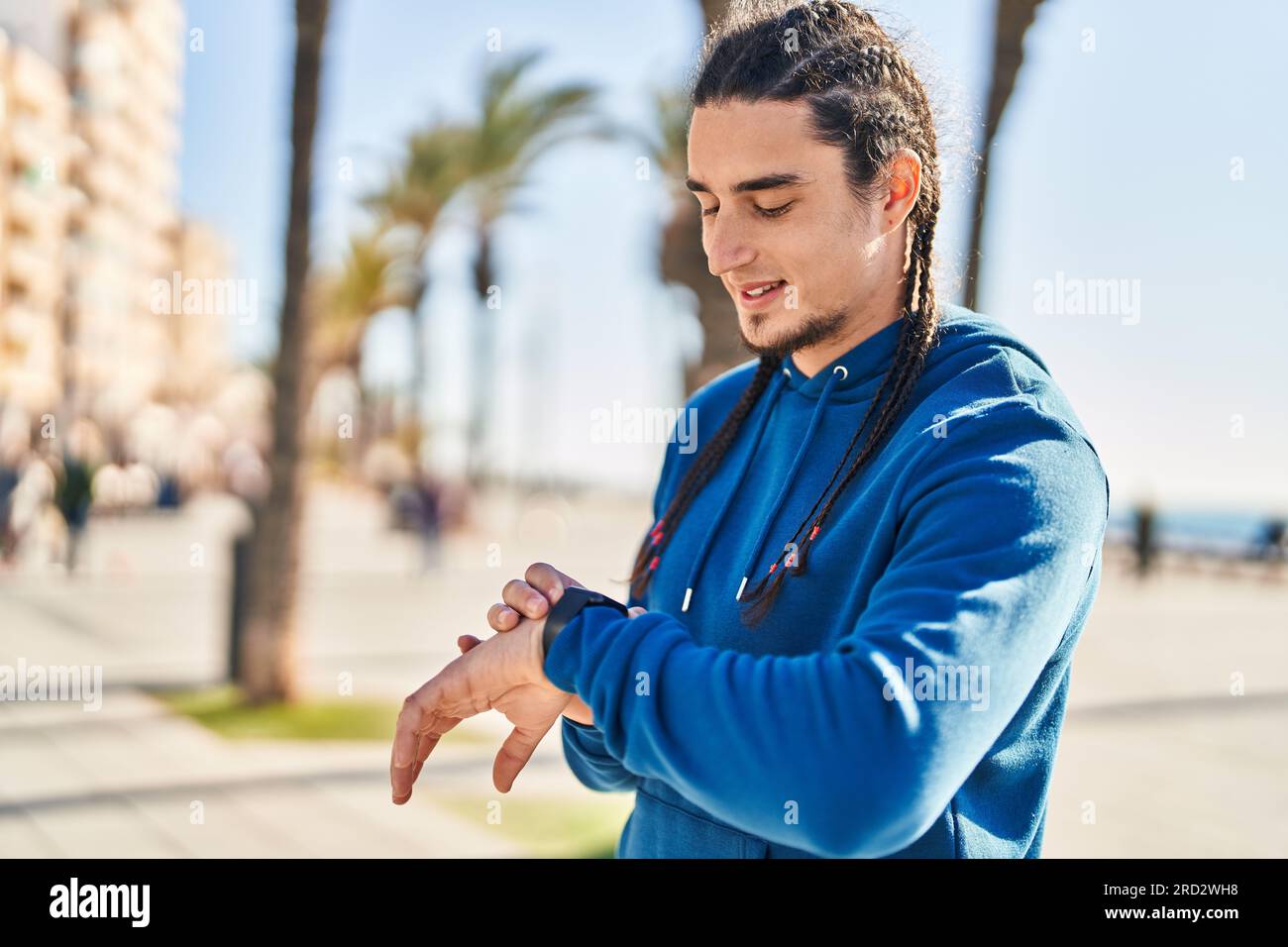 Young man smiling confident using stopwatch at seaside Stock Photo - Alamy