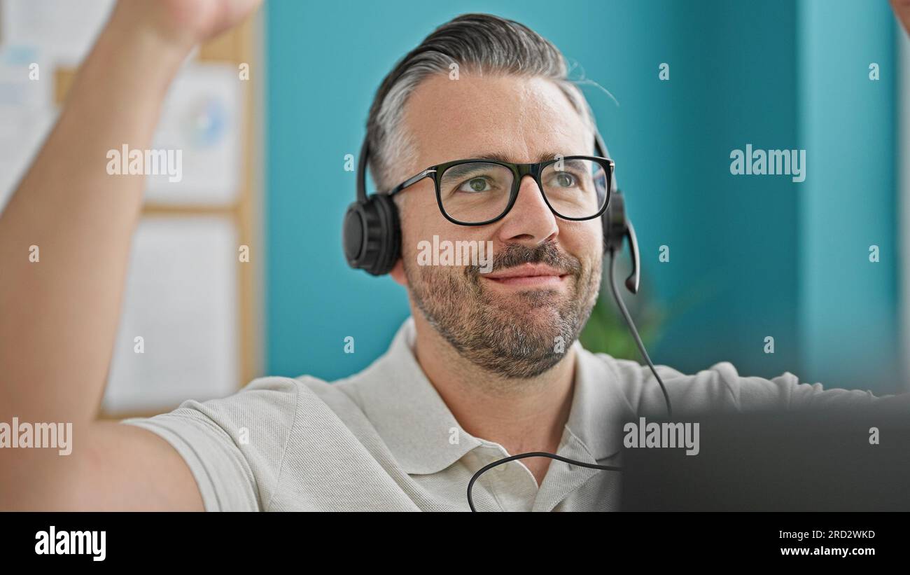 Grey-haired man business worker wearing headphones celebrating at the ...