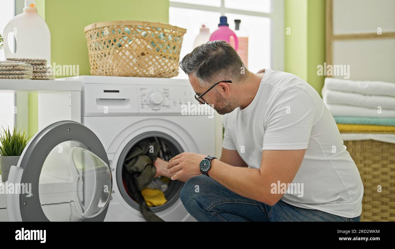 Grey-haired man washing clothes at laundry room Stock Photo - Alamy