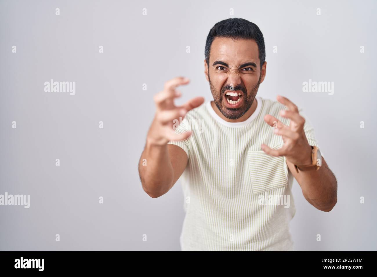 Hispanic man with beard standing over isolated background shouting ...