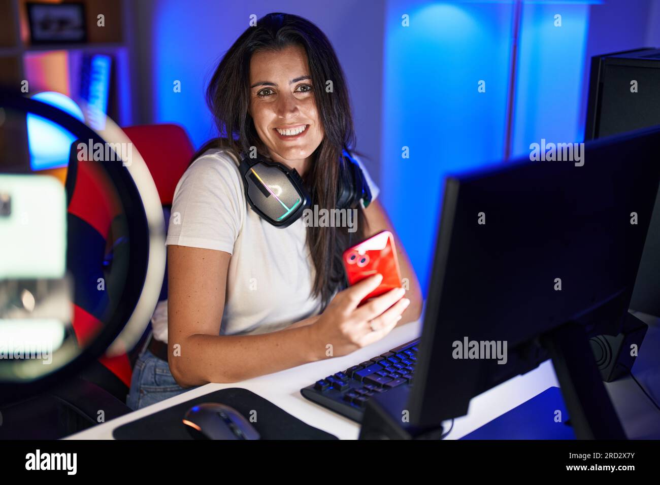 Young beautiful hispanic woman streamer using computer and smartphone ...
