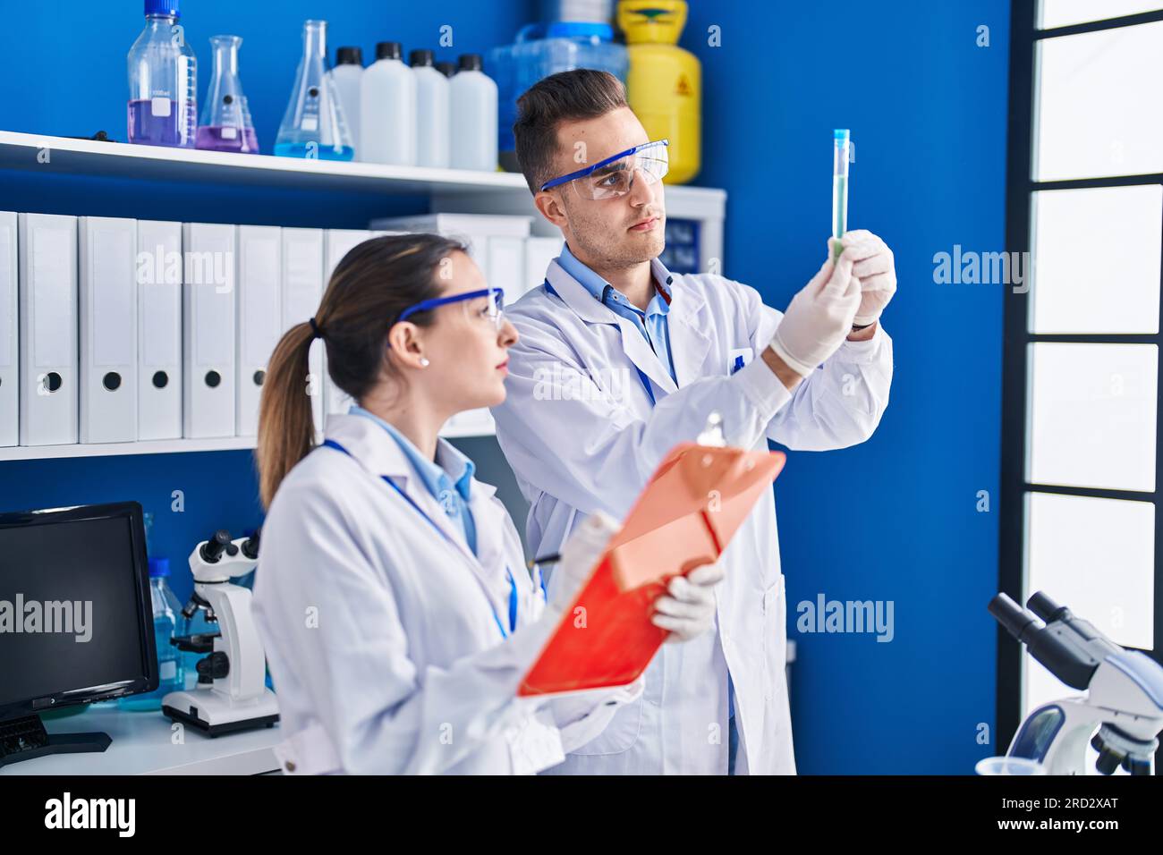 Man and woman scientists holding test tubes write on document at ...