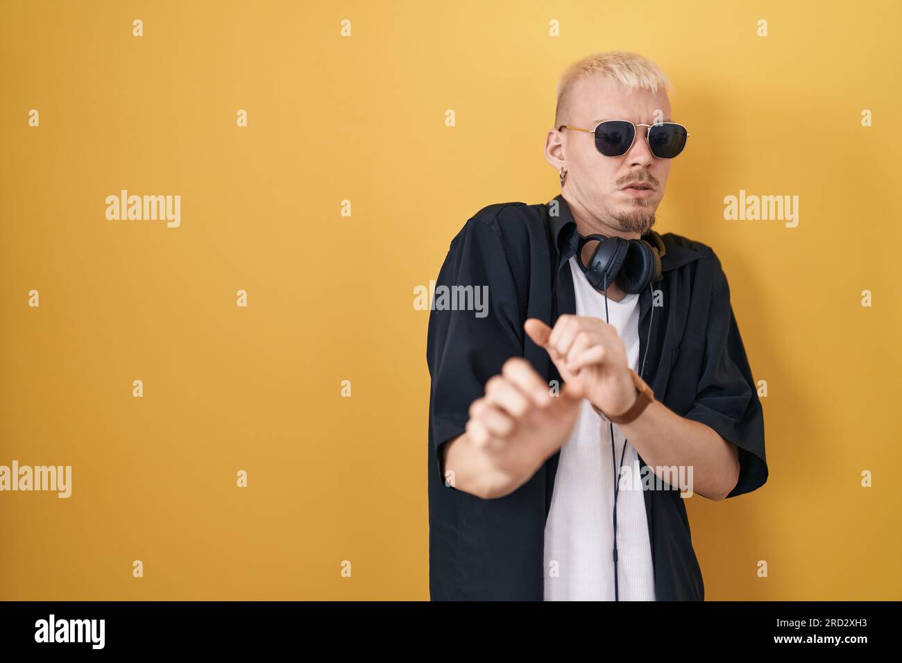 Young caucasian man wearing sunglasses standing over yellow background ...
