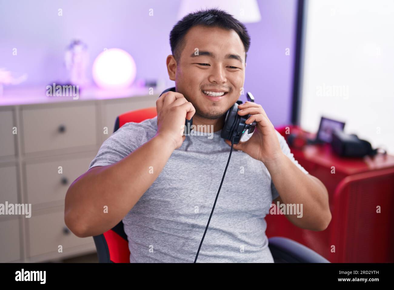 Young chinese man streamer smiling confident holding headphones at ...