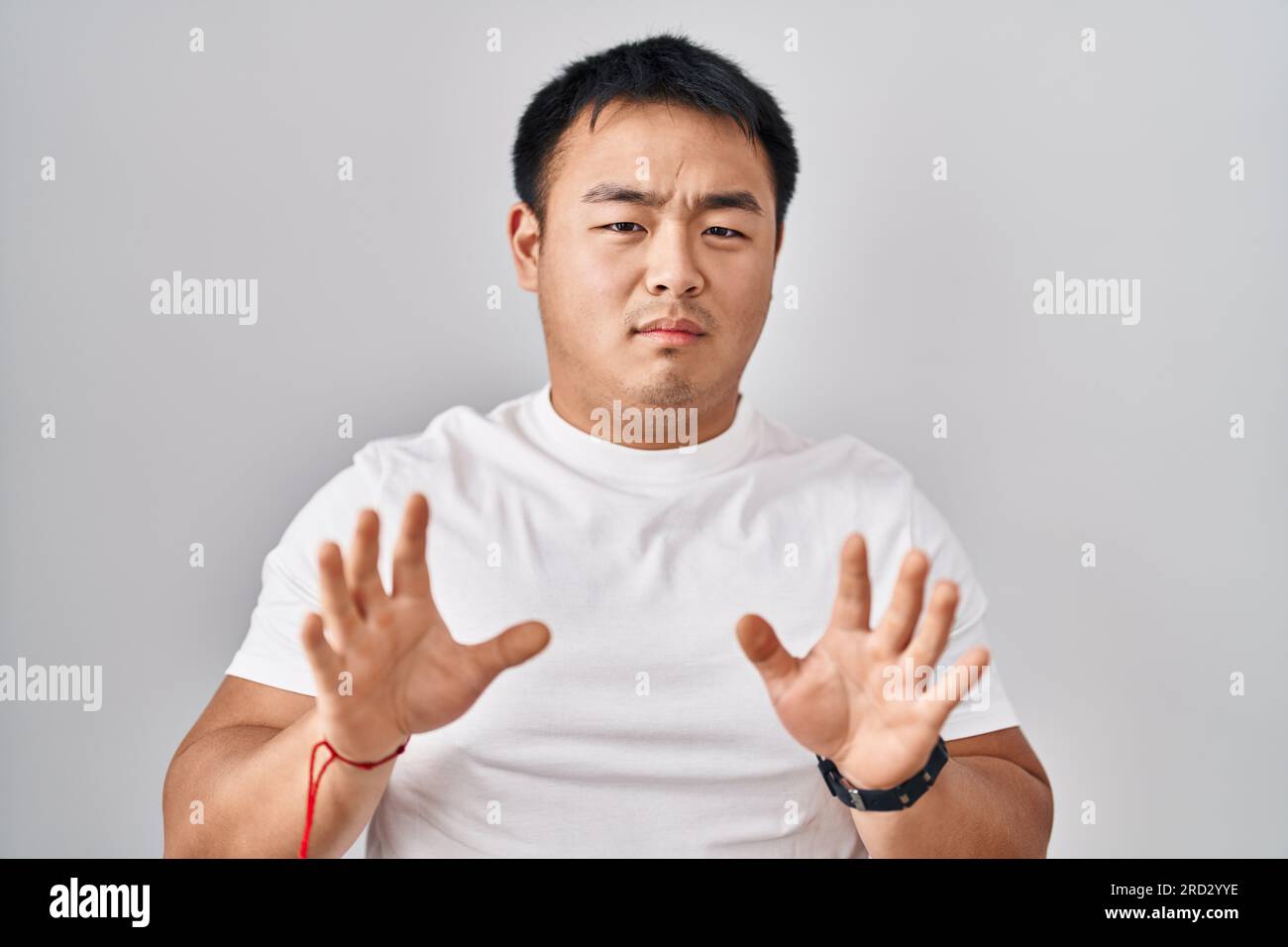 Young chinese man standing over white background moving away hands ...