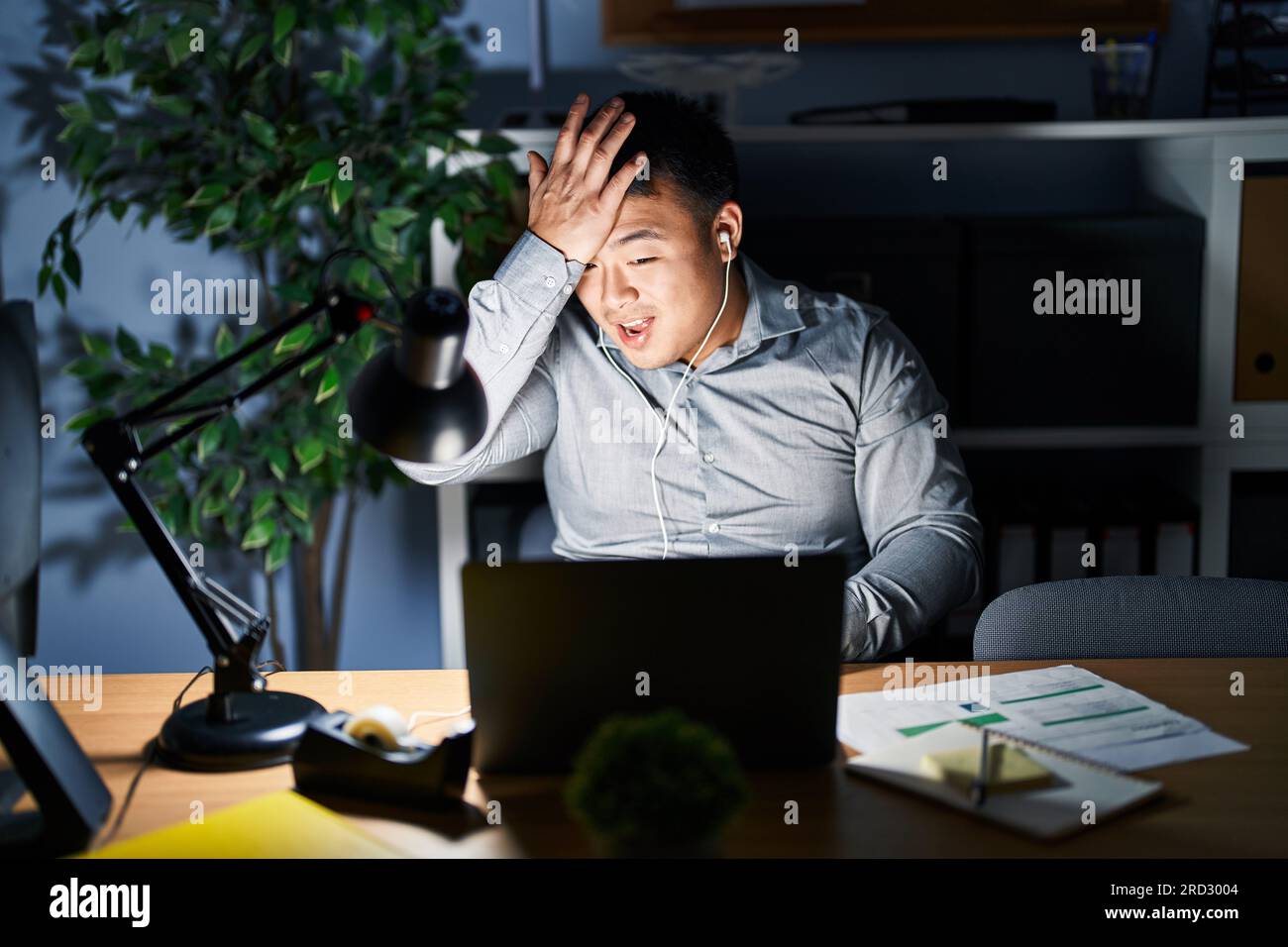 Young chinese man working using computer laptop at night surprised with ...