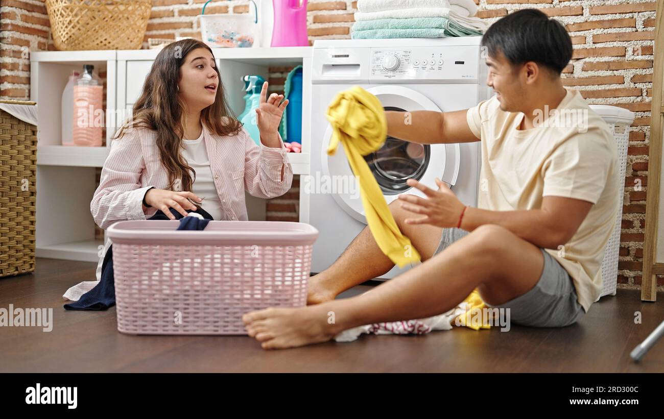 Man and woman couple throwing clothes each other playing at laundry ...