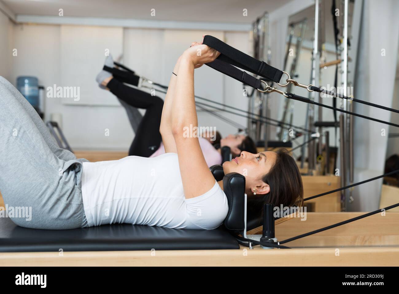 Sportswoman stretching body on pilates chair while doing forward bends ...