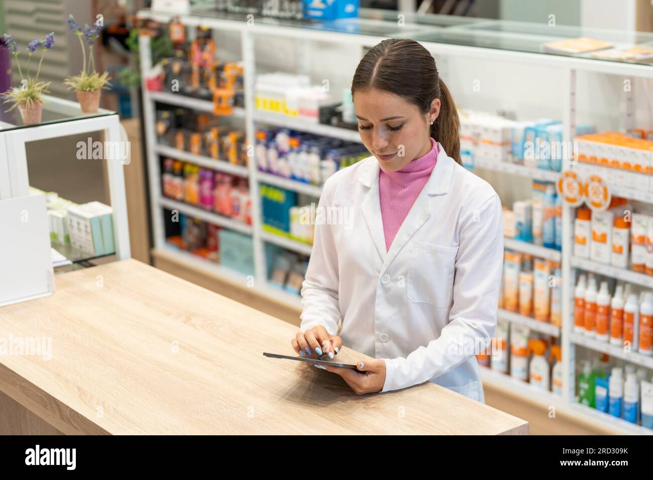 Female pharmacist looking at the screen of a digital tablet in the ...