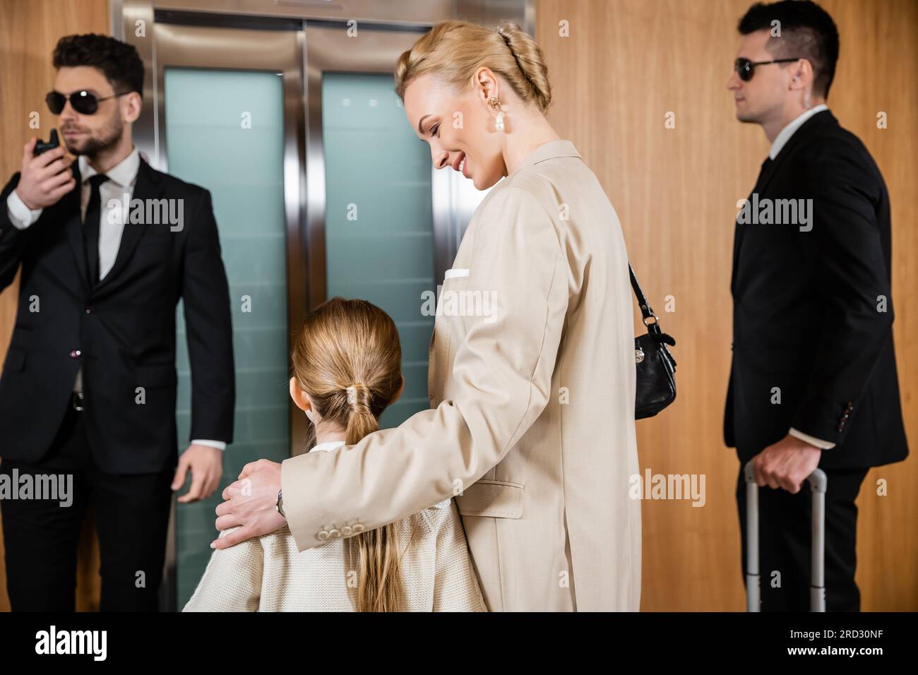 happy mother hugging child while standing near hotel elevator and ...