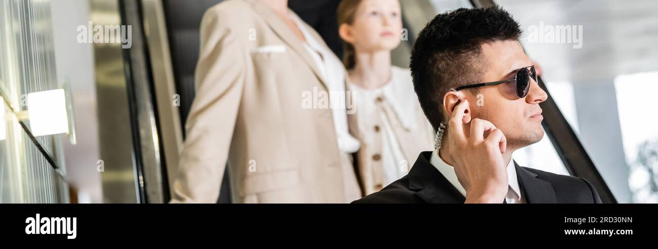 personal security concept, bodyguard communicating through earpiece ...